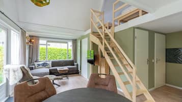 Uma sala de estar moderna com escada de madeira, um conjunto de sofá e uma mesa de jantar.