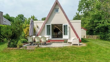Uma casa triangular com um pátio, incluindo uma mesa e cadeiras.
