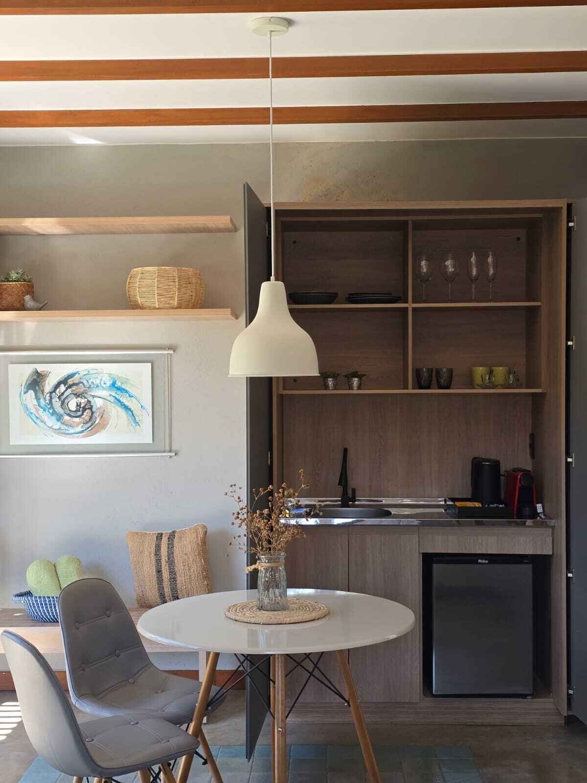 Cozinha moderna com ilha central, iluminação pendente e área de refeições com mesa redonda e cadeiras.