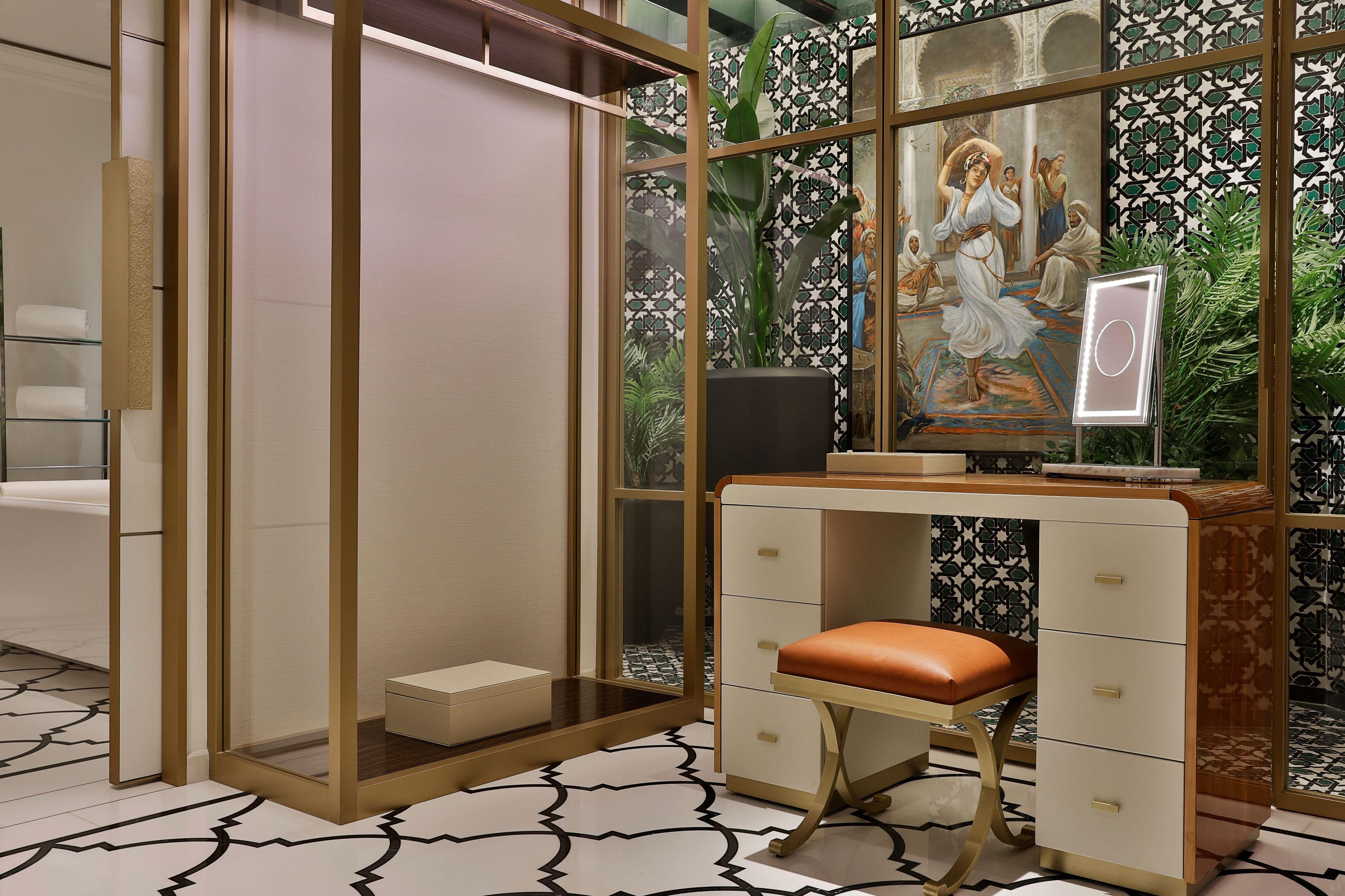 Quarto com divisória de vidro, escrivaninha com gavetas, cadeira, espelho e parede revestida com um mural.