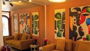 Uma sala de estar com dois sofás, uma mesa de centro e quadros abstratos nas paredes.