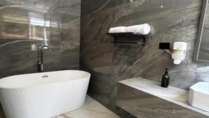 Um banheiro moderno com banheira livre, piso de mármore e nicho com amenities.