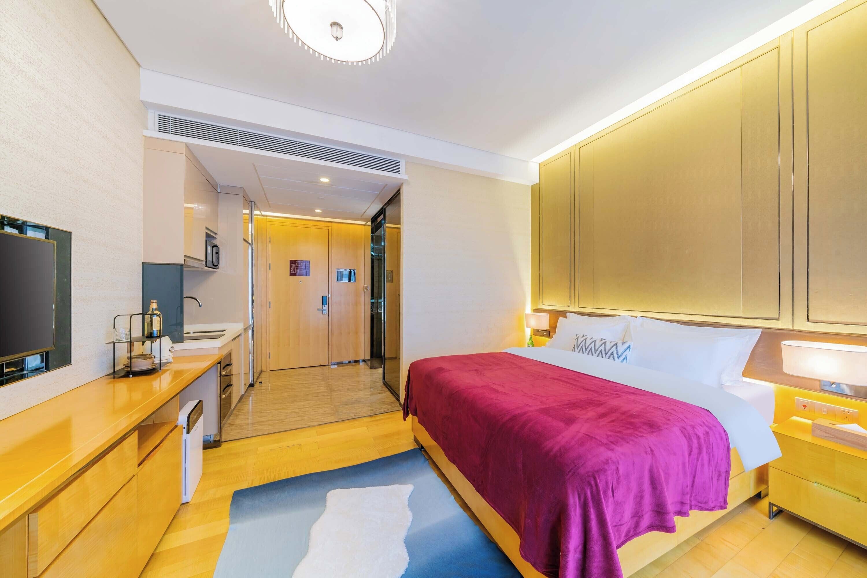 Quarto de hotel moderno com cama, televisão, escrivaninha e banheiro.