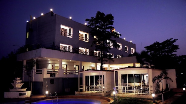 Um hotel moderno com piscina, várias varandas e fachada bem iluminada.
