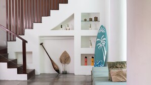 Uma escada com corrimãos de madeira, uma prancha de surf e uma parede com prateleiras exibindo objetos decorativos.