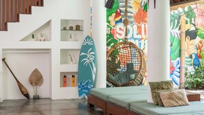 Quarto com uma cama, uma prancha de surf, uma cadeira suspensa e uma escada.