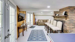 Um quarto com mesa de pingue-pongue, sofá e lareira de tijolos.