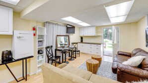 Um espaço de estar compacto com cozinha compacta, área de refeições e sala de estar com sofá e cadeiras.