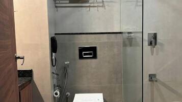 Um banheiro moderno com box de vidro, vaso sanitário, lixeira e porta-toalhas.