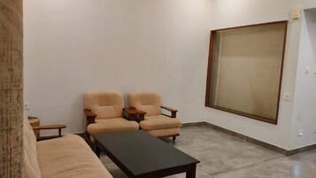 Um quarto com sofá, duas poltronas e uma mesa de centro.