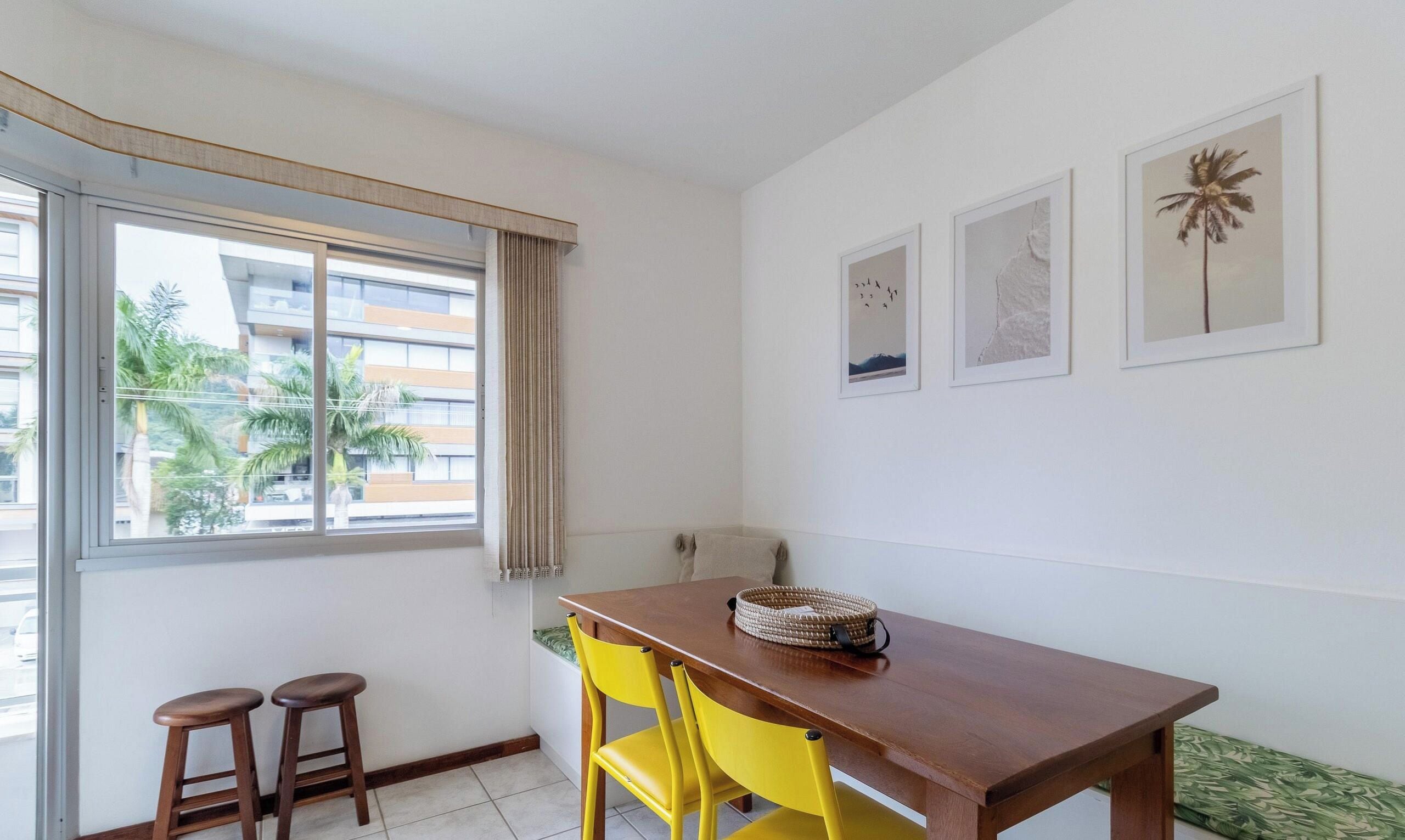 Uma sala de jantar com mesa de madeira, cadeiras amarelas e um cesto de palha.