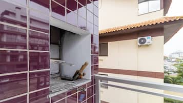 Um edifício com varanda, janela com grade de metal e unidade de ar condicionado na parede externa.