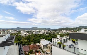Terraço no telhado com vista para a cidade, incluindo edifícios e áreas verdes.