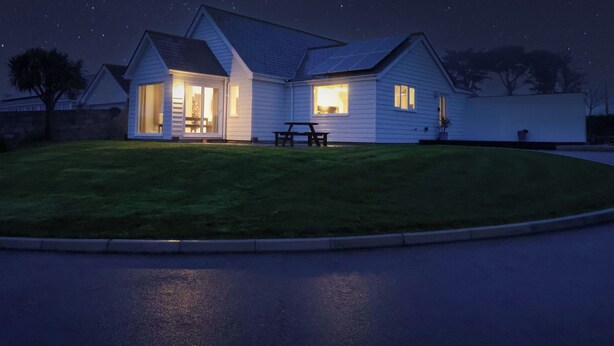 Uma casa com varanda espaçosa, área de refeições e gramado bem cuidado.