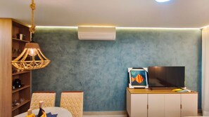 Quarto com ventoinha no teto, luminária pendente, televisão de tela plana em um armário de madeira e ar-condicionado fixado na parede.