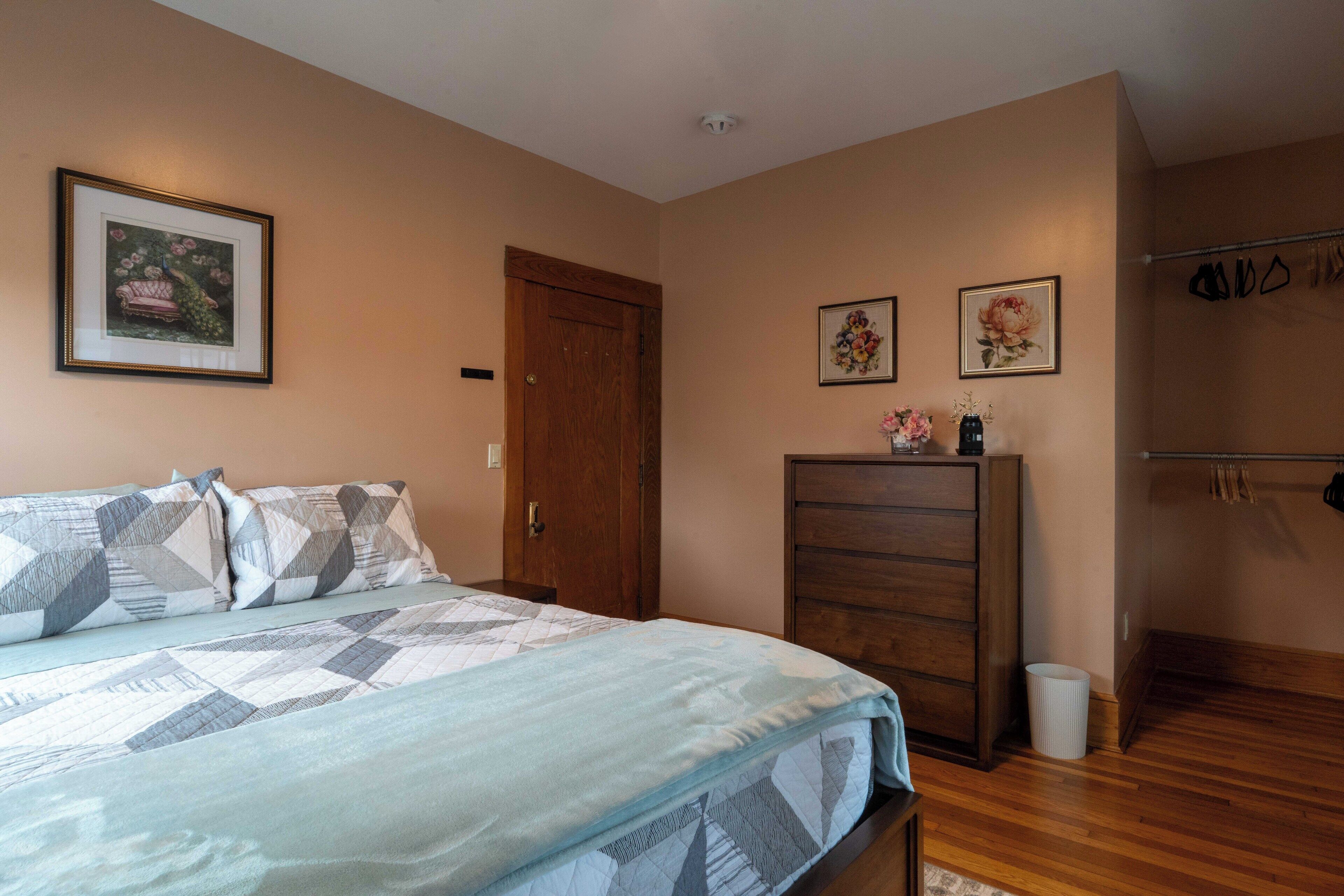 Quarto com cama, cômoda e obra de arte na parede.