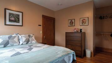 Quarto com cama, cômoda e obra de arte na parede.
