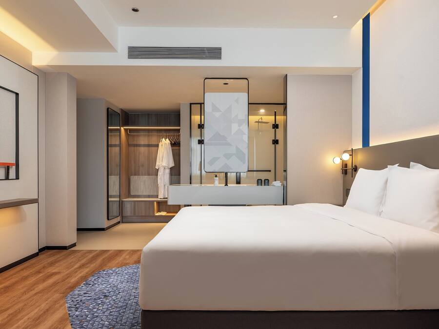 Quarto de hotel moderno com uma cama grande, televisão integrada, toucador com espelho e closet espaçoso.