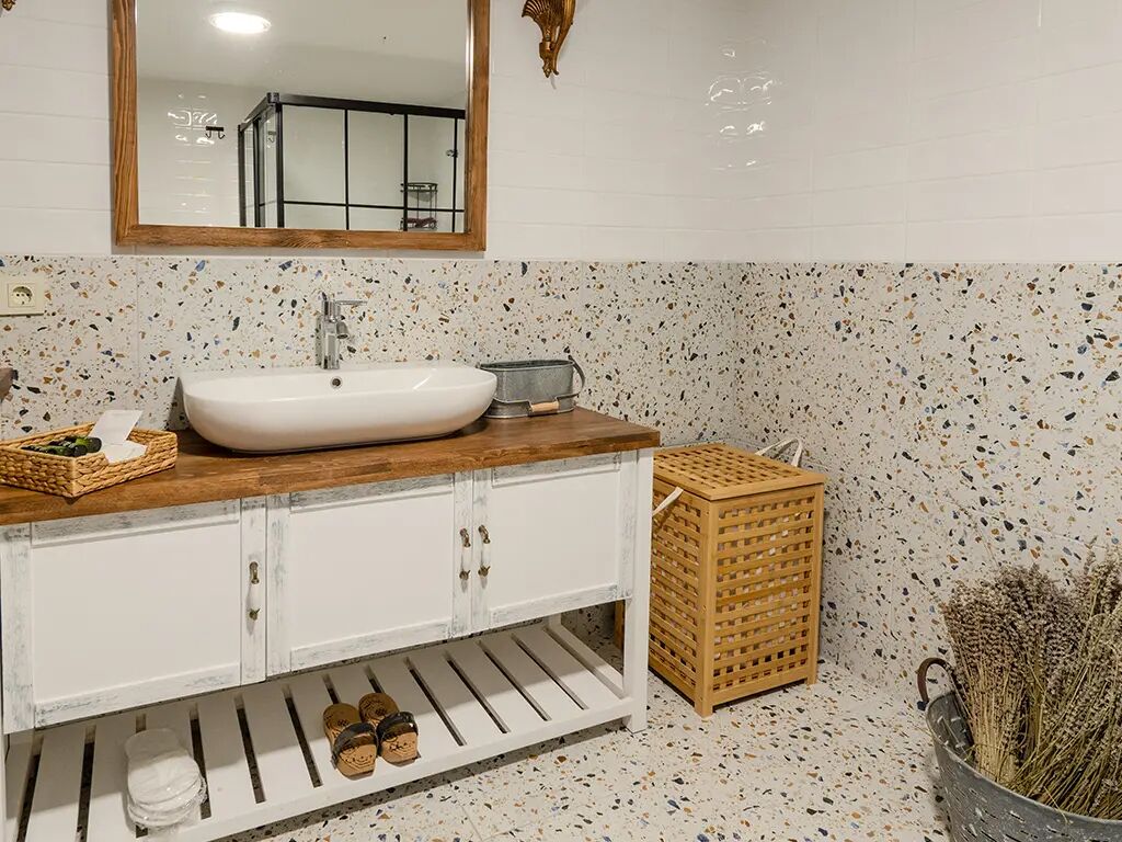 Casa de banho com lavatório branco, toucador de madeira e painel de parede com padrão pontilhado.
