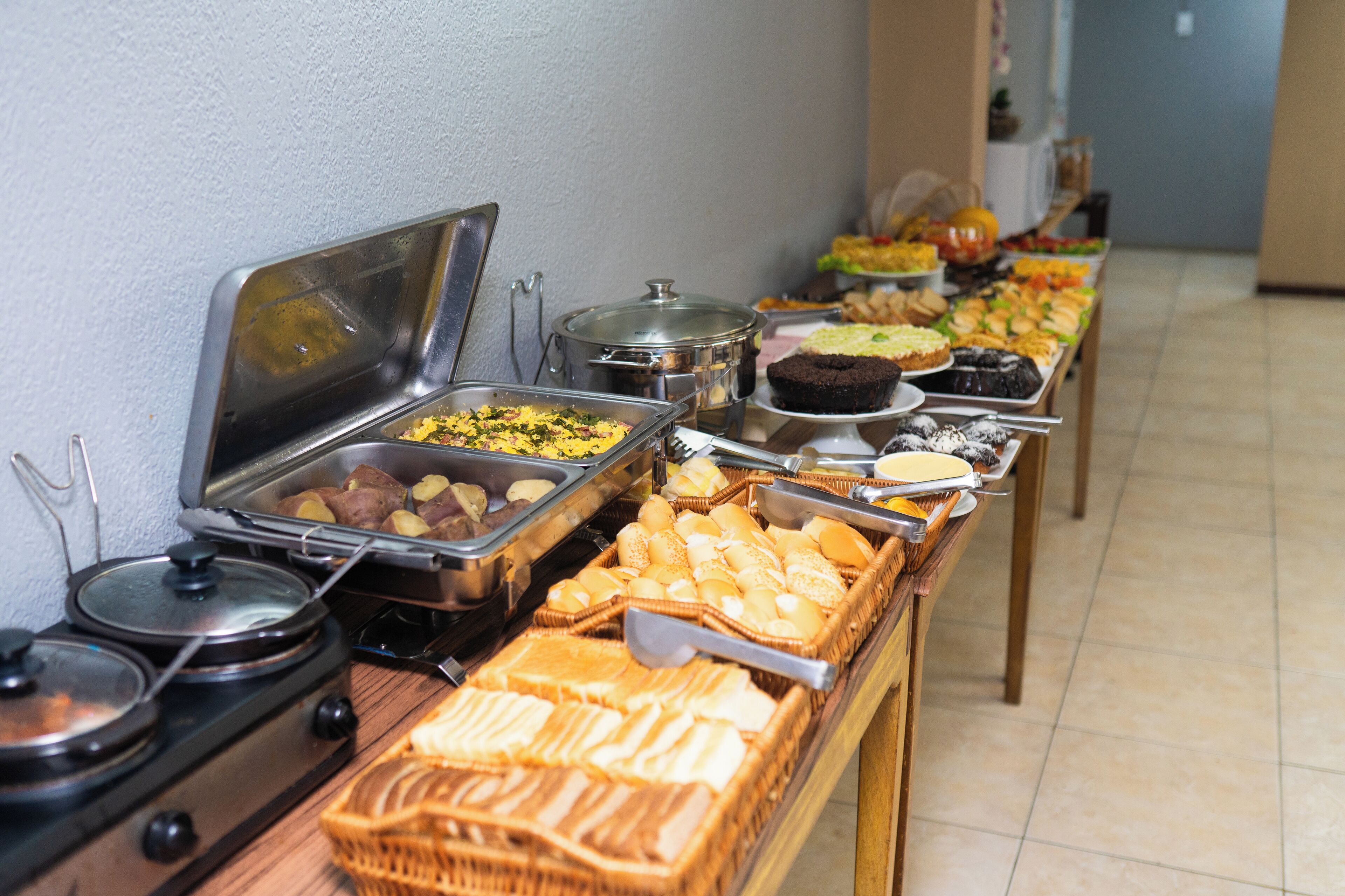 Uma mesa de buffet com diversos alimentos e um fogão com panelas.