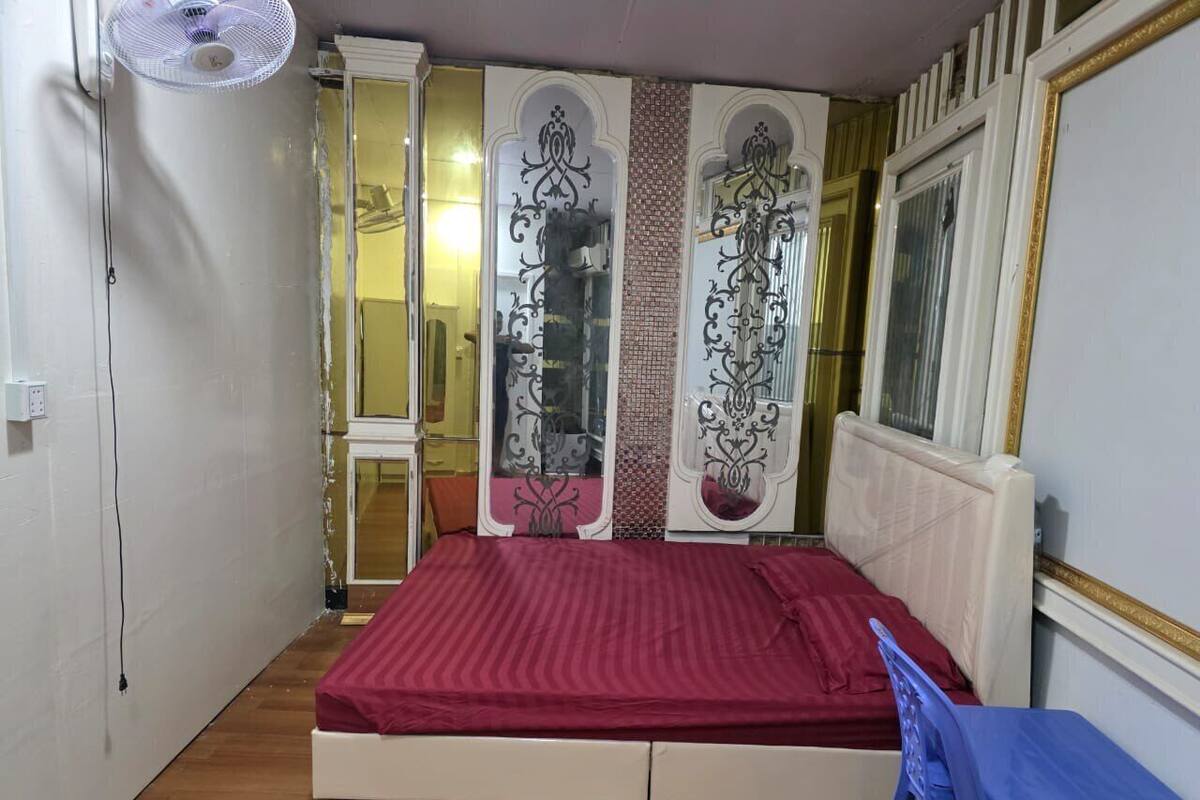 Quarto com cama, uma cadeira, um ventilador e painéis decorativos.