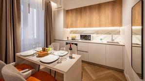 Uma cozinha moderna com micro-ondas, pia e armários de madeira. Há uma mesa de jantar posta com pratos, copos e uma garrafa de vinho.