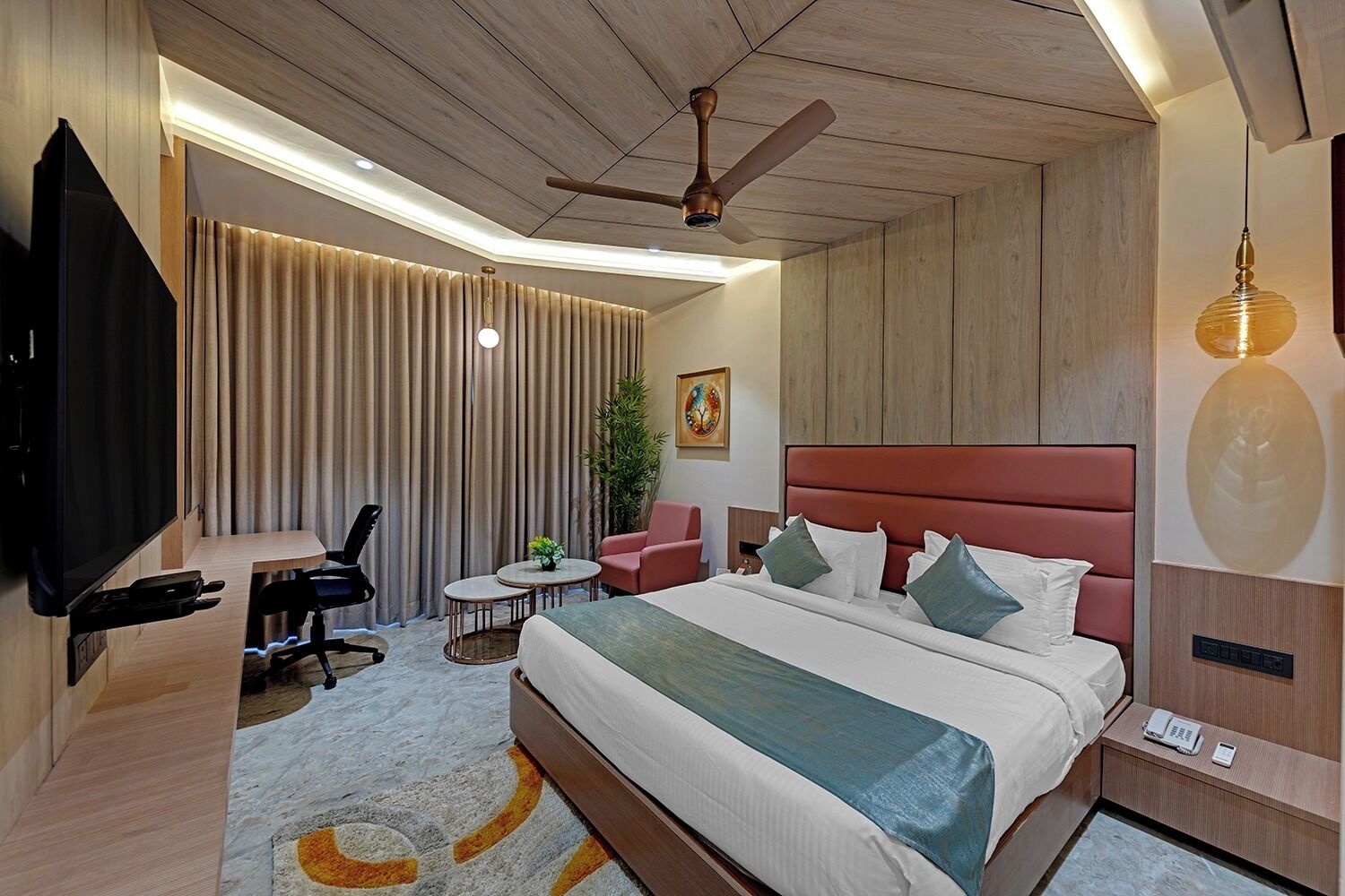 Quarto de hotel moderno com uma cama grande, uma escrivaninha, uma cadeira e uma televisão.