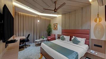 Quarto de hotel moderno com uma cama grande, uma escrivaninha, uma cadeira e uma televisão.