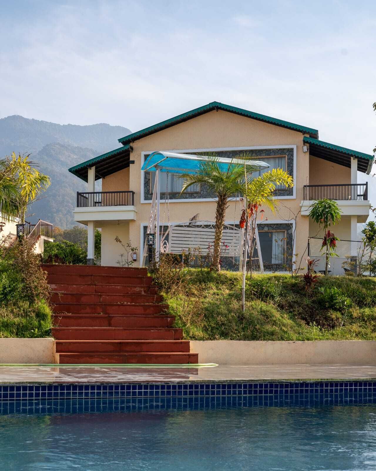 Uma casa de dois andares com piscina na frente.