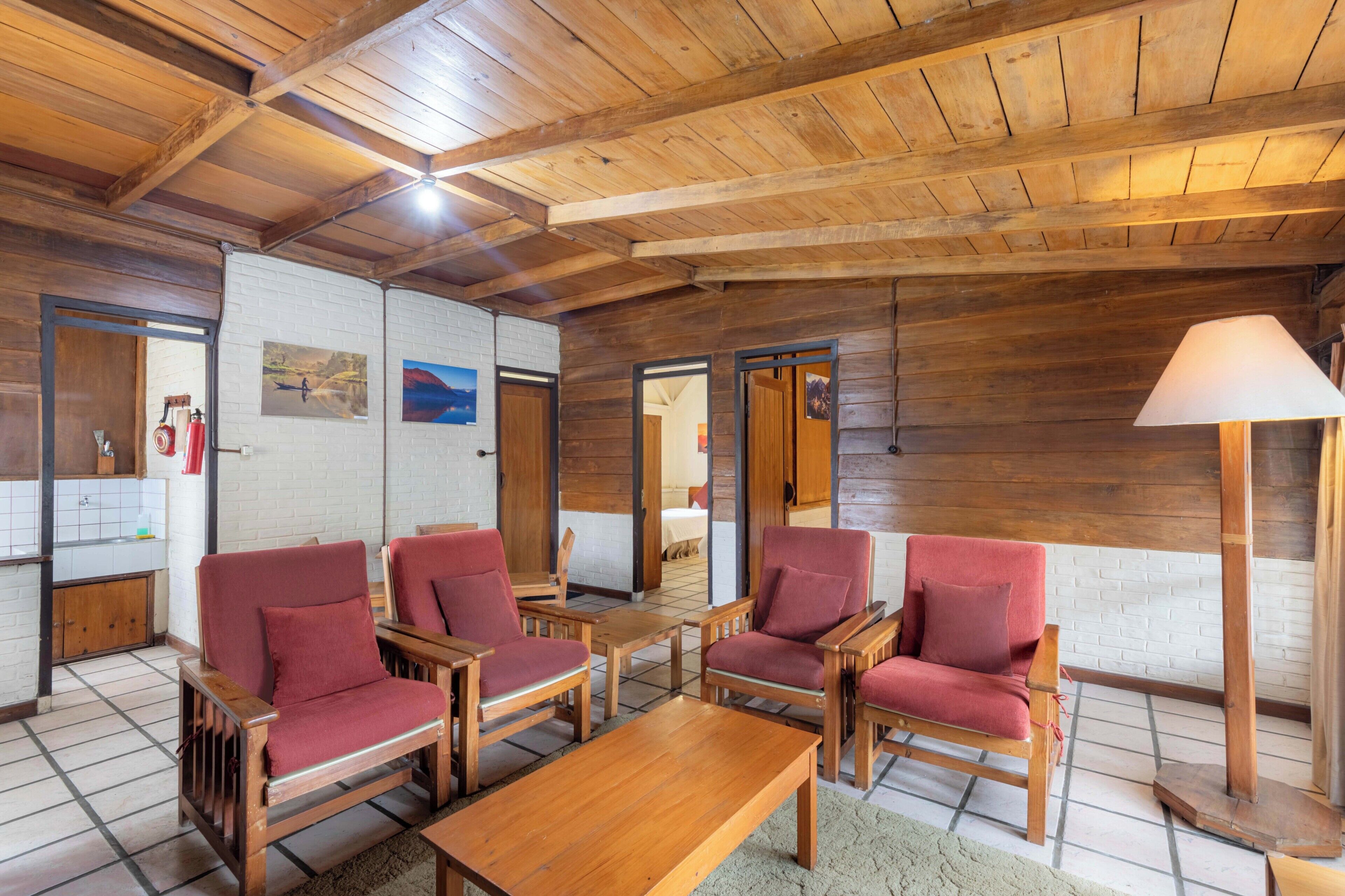Quarto aconchegante com móveis de madeira, teto de madeira e parede de tijolos brancos.