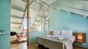 Quarto com cama, luminárias de cabeceira, piso de madeira e vista para uma sala de jantar.
