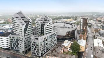 Uma área urbana moderna com um edifício curvo em destaque identificado como 'Nokia Arena' e vários edifícios altos adjacentes.