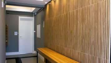 Um corredor com um banco de madeira, uma porta e uma parede texturizada.