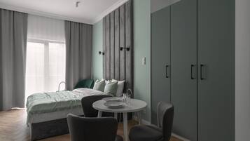 Quarto moderno com cama, mesa de jantar redonda, duas cadeiras e um guarda-roupa.