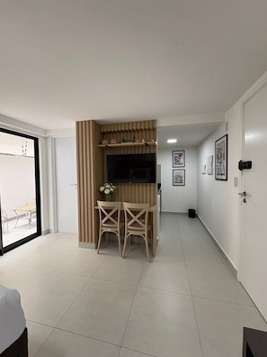 Um interior moderno com área de refeições, televisão e obras de arte nas paredes.
