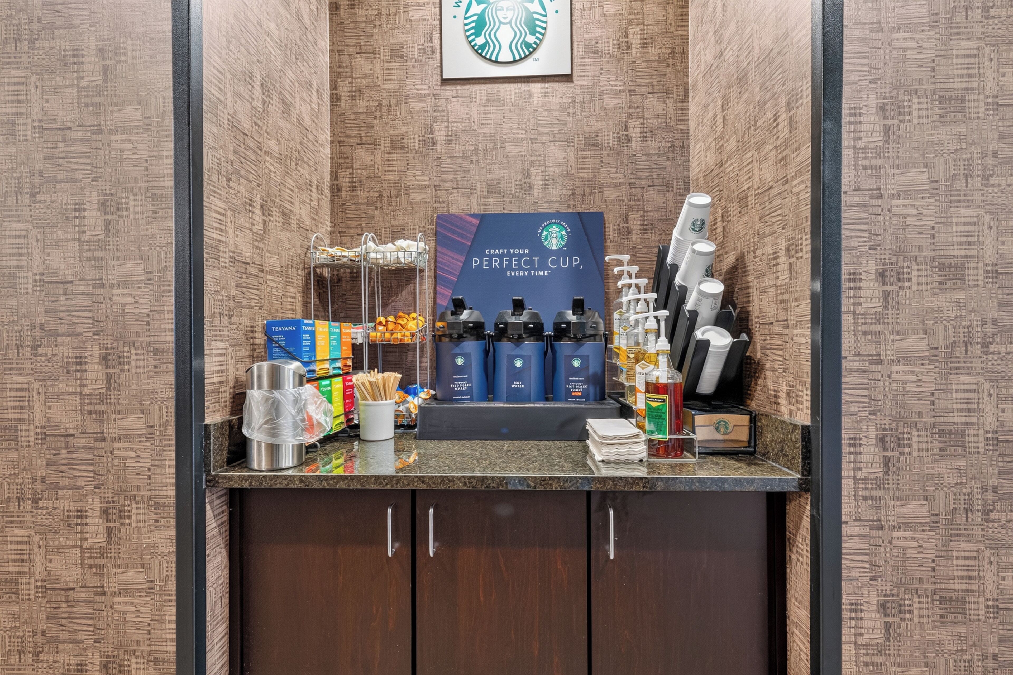 Uma estação de café com o logotipo da Starbucks, um letreiro convidando a criar a xícara perfeita e diversos equipamentos para preparo de café.