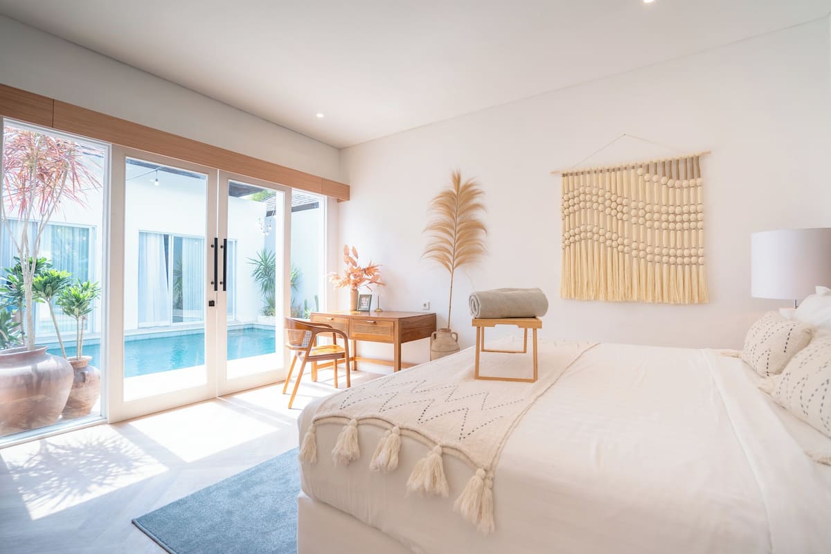 Quarto moderno com uma cama grande, uma escrivaninha e vista para uma piscina.