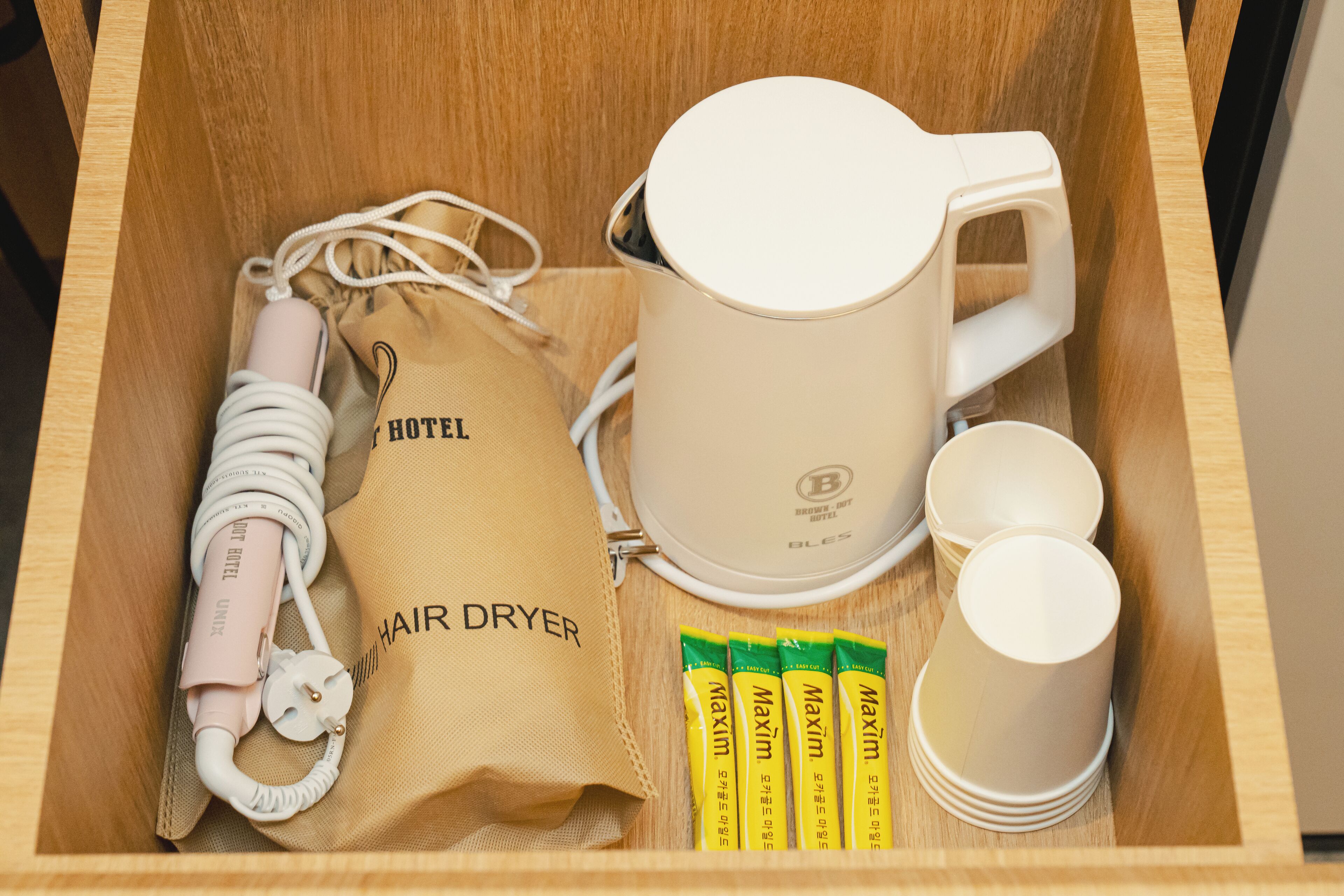 Uma caixa de madeira com um secador de cabelo, uma caneca e embalagens de produtos para cabelo.