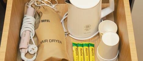 Uma caixa de madeira com um secador de cabelo, uma caneca e embalagens de produtos para cabelo.