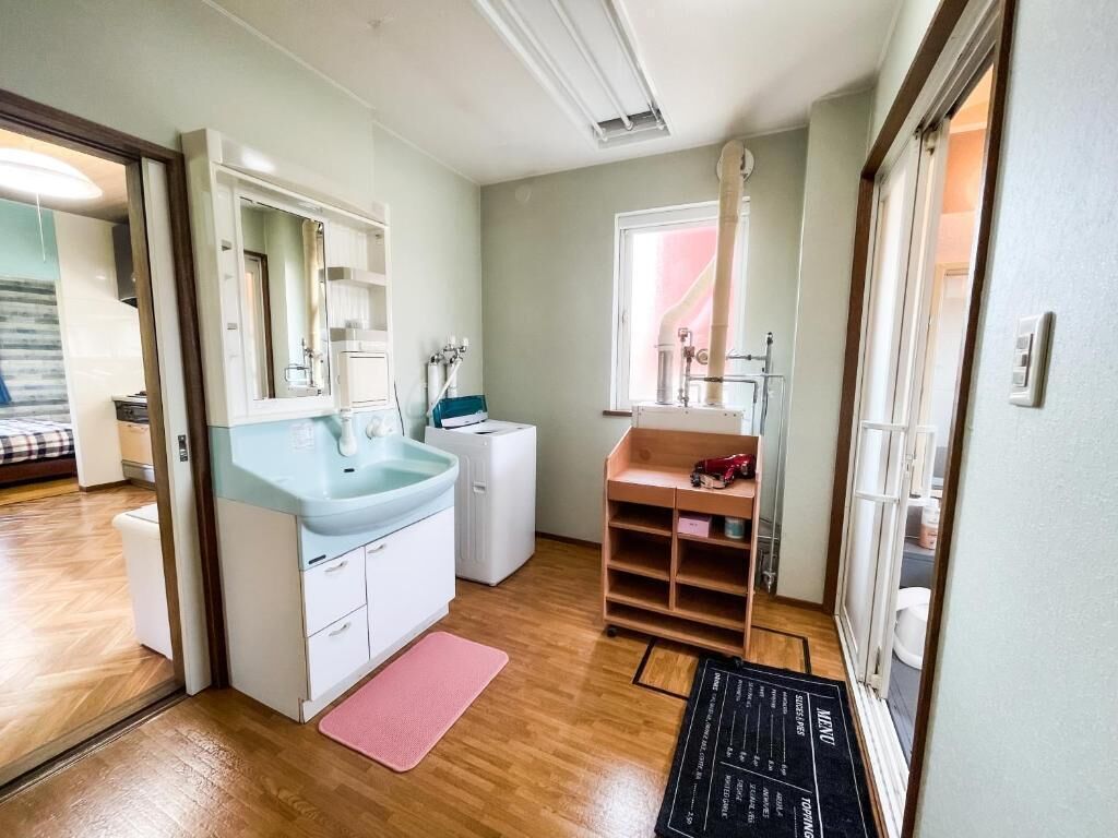 Quarto compacto com pia, espelho e prateleiras.