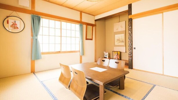 Um quarto japonês tradicional com tatames, uma mesa de madeira e portas deslizantes.