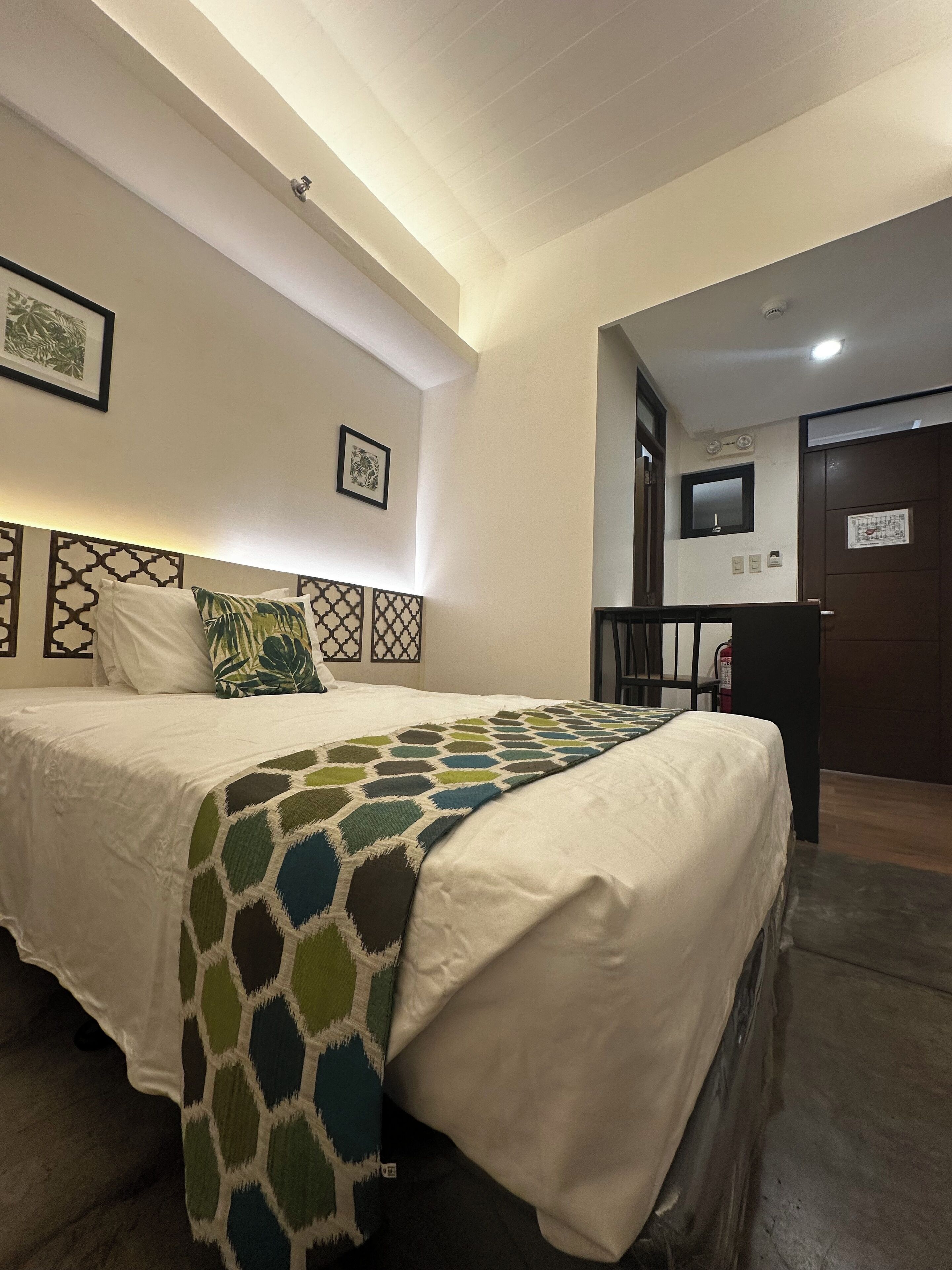 Quarto de hotel com cama, escrivaninha e uma cadeira.
