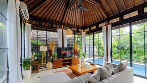 Uma sala de estar moderna com uma televisão grande, assentos confortáveis e vista para uma piscina.