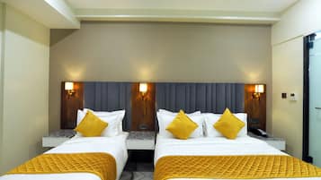 Quarto de hotel com duas camas, cada uma com cabeceira, mesas de cabeceira e luminárias.