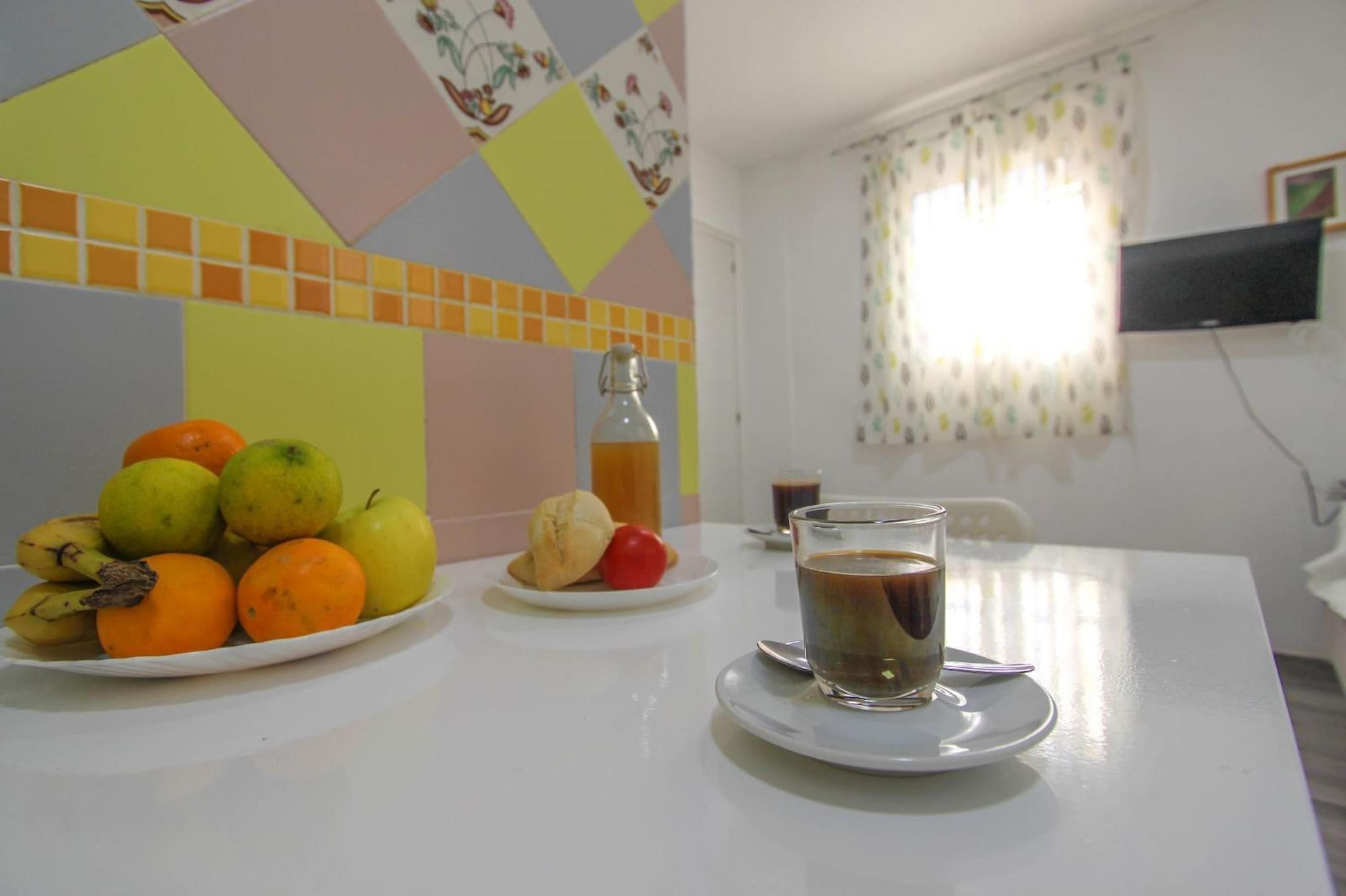 Uma mesa de jantar com uma travessa de fruta, um copo de café e uma garrafa de água.
