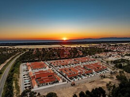 Vista aérea de uma área residencial com muitas casas, uma estrada principal e um corpo de água ao fundo.