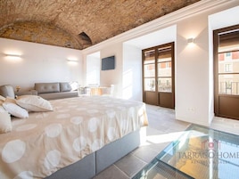 Quarto com cama, sofá, mesa de jantar e vista para o exterior.