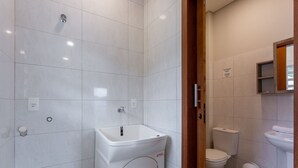 Casa de banho moderna com lavatório branco, sanita e zona de duche.
