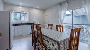 Uma cozinha moderna com armários brancos, uma mesa de jantar com cadeiras e uma janela grande com cortinas.