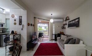 Uma sala moderna com tapete vermelho, sofá branco e área de jantar com mesa e cadeiras.